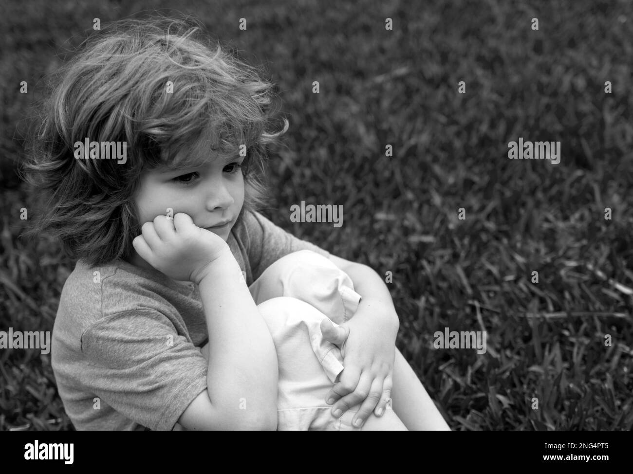 Its sad. Little child sad boy sit in grass, summer. Childhood, youth ...