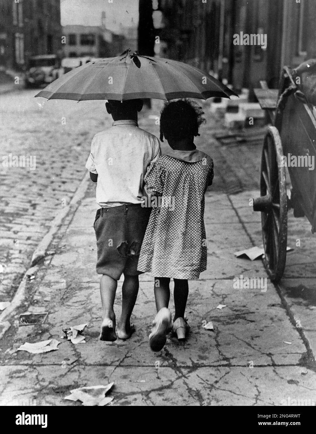 Two children walk under an umbrella down a Philadelphia street, date ...