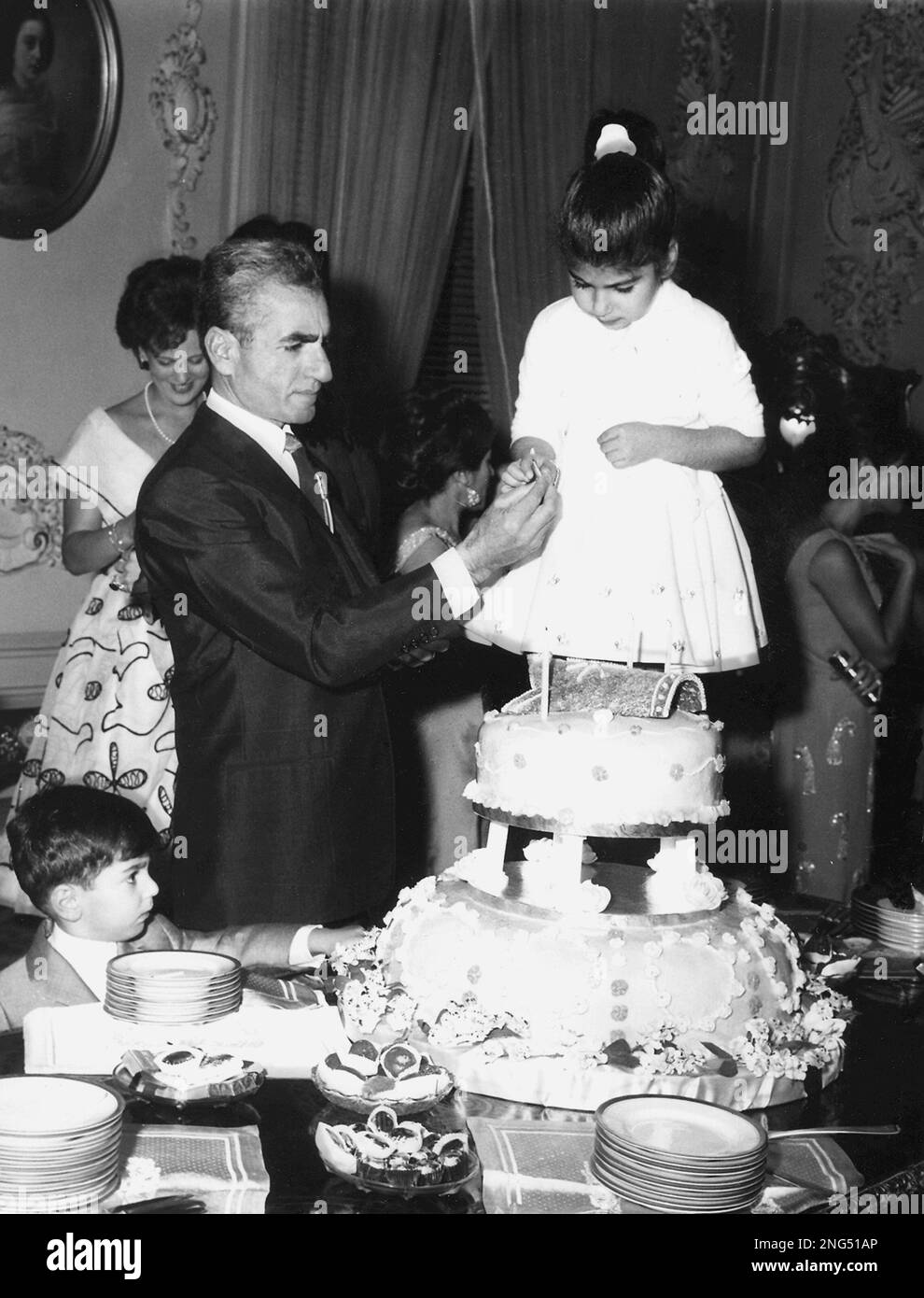 Shah of Iran, Mohammad Reza Pahlavi, helps the daughter of Ambassador ...