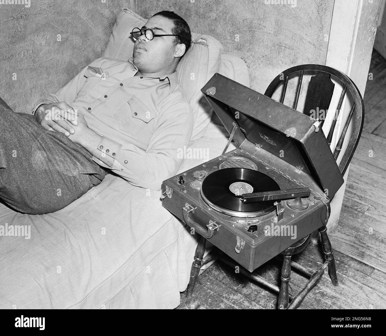 Heavyweight boxing champion Joe Louis relaxes listening to music at his ...