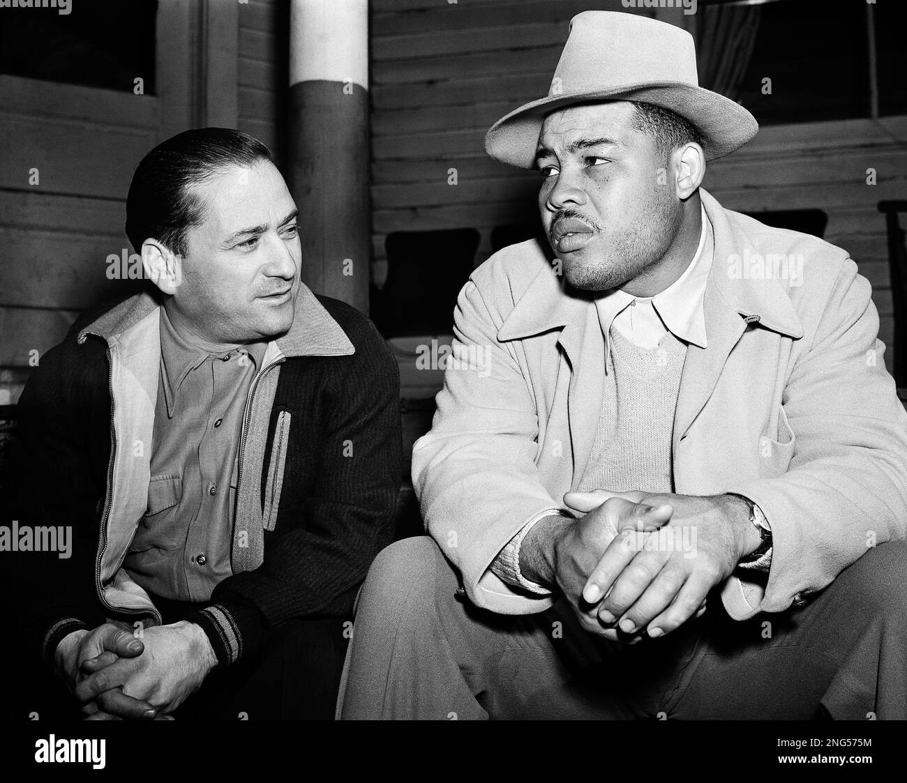 Joe Louis and his trainer, Mannie Seamon, at left, sit on a hotel porch ...