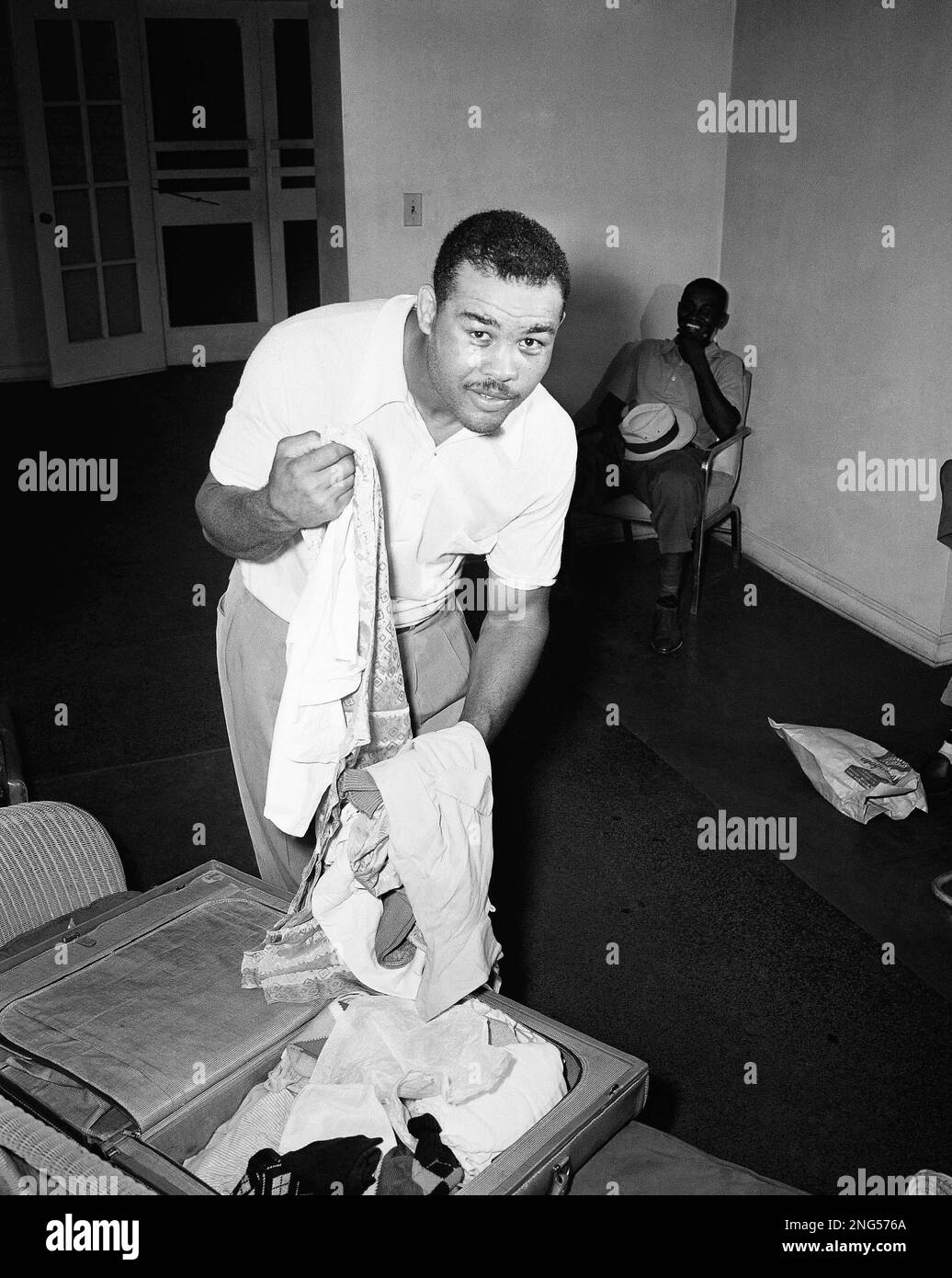 Joe Louis, retired heavyweight boxing champion, unpacks a bag on ...