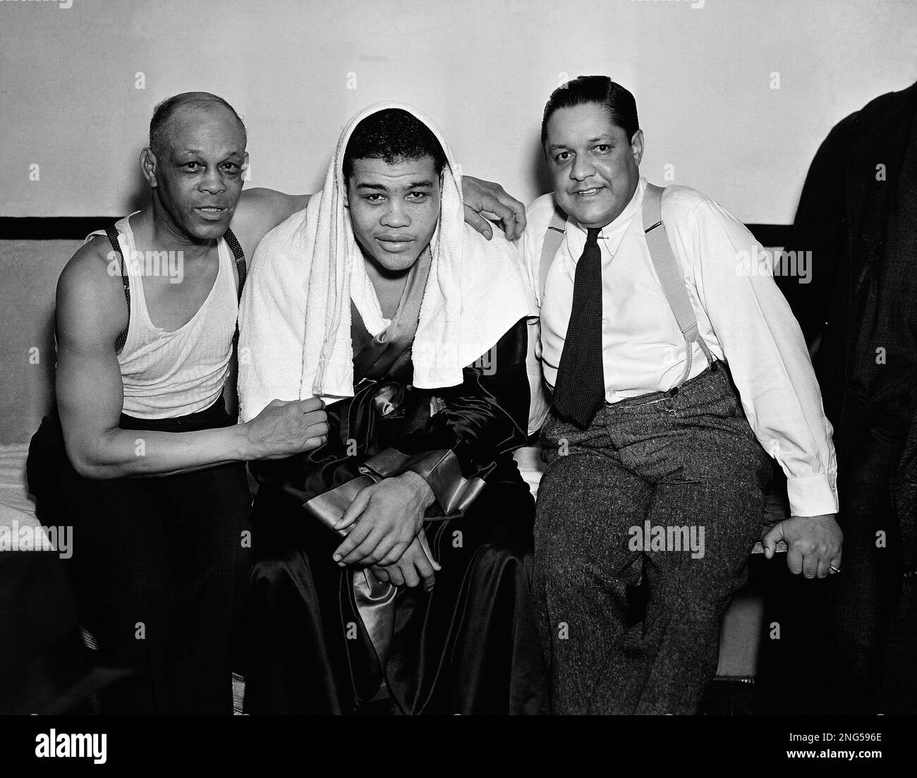 World heavyweight champ Joe Louis, center, sits in his dressing room in ...