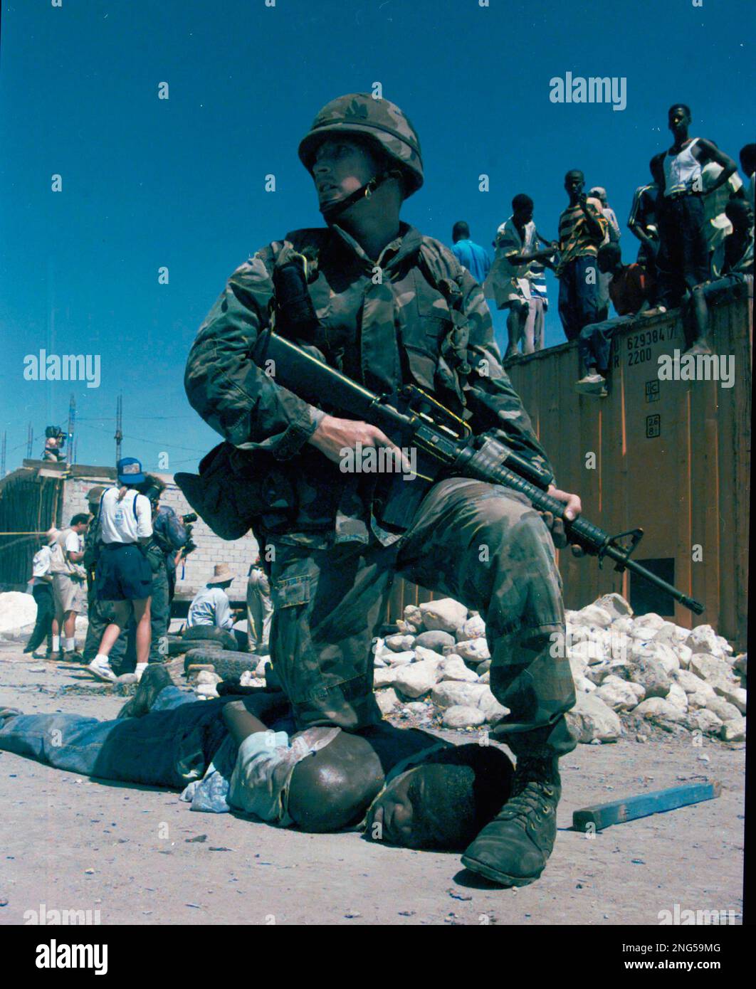 A U.S. Army soldier holds a Haitian man down on the ground during a ...