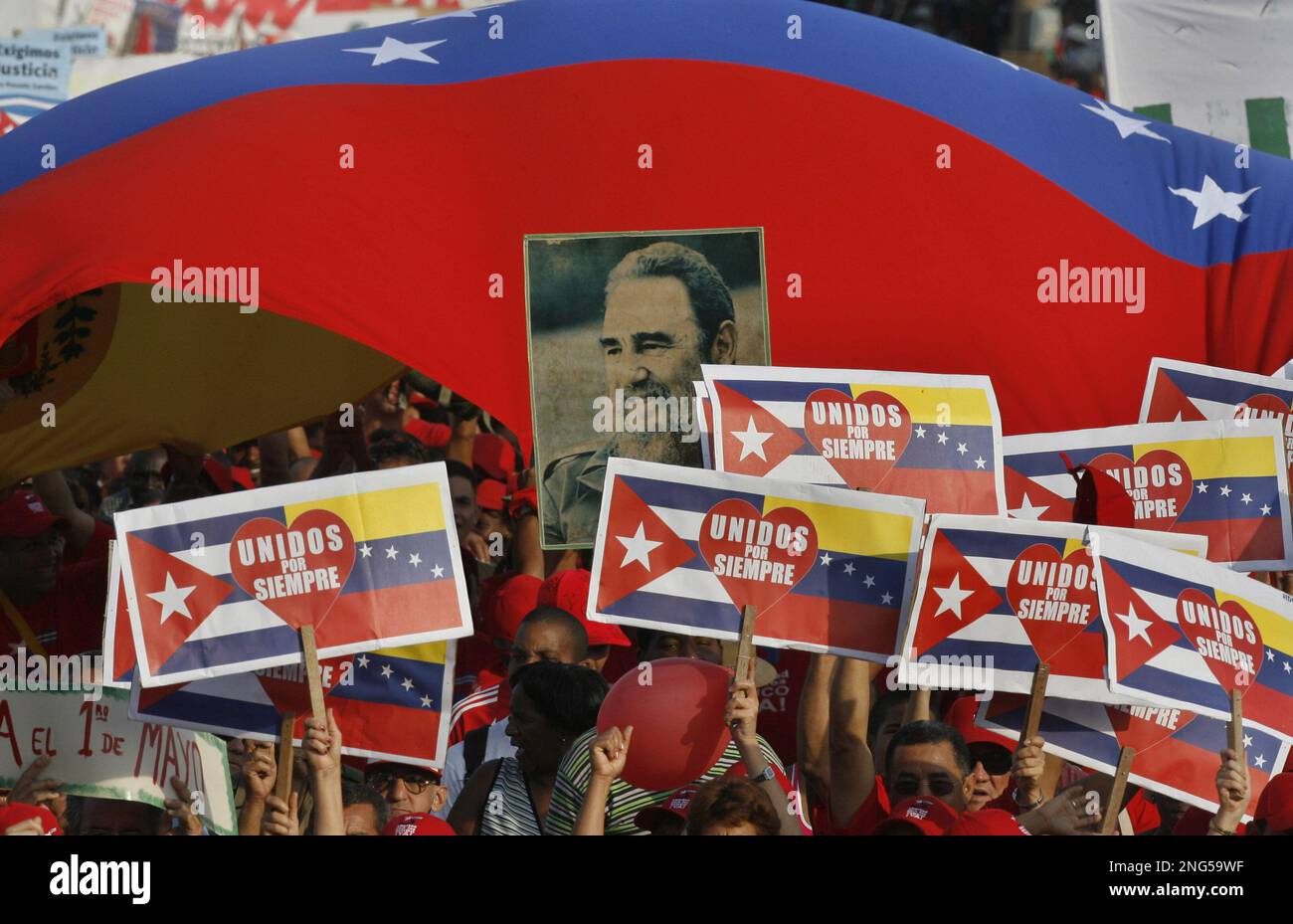 Demonstrators hold signs with the Venezuelan and Cuban flags and a ...