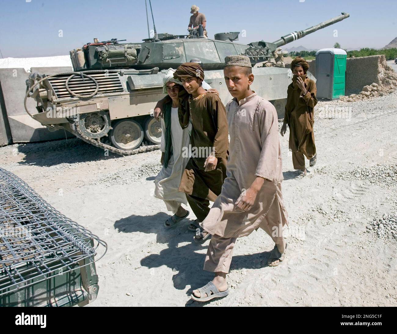 Local Afghani workers walk past a Canadian Leopard I tank at the ...