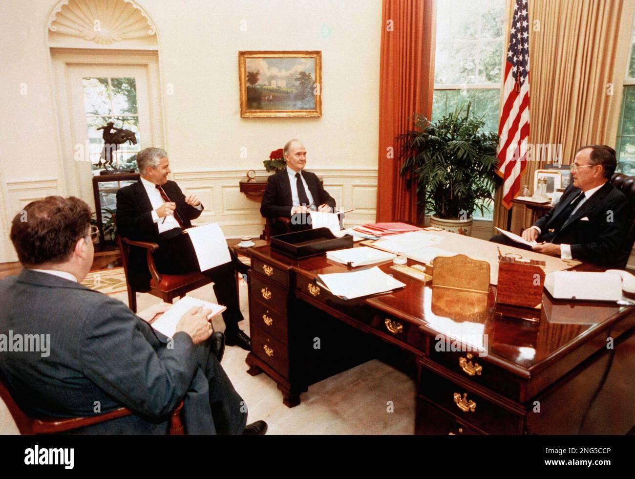 President George H.W. Bush sits behind his new desk in the Oval Office ...
