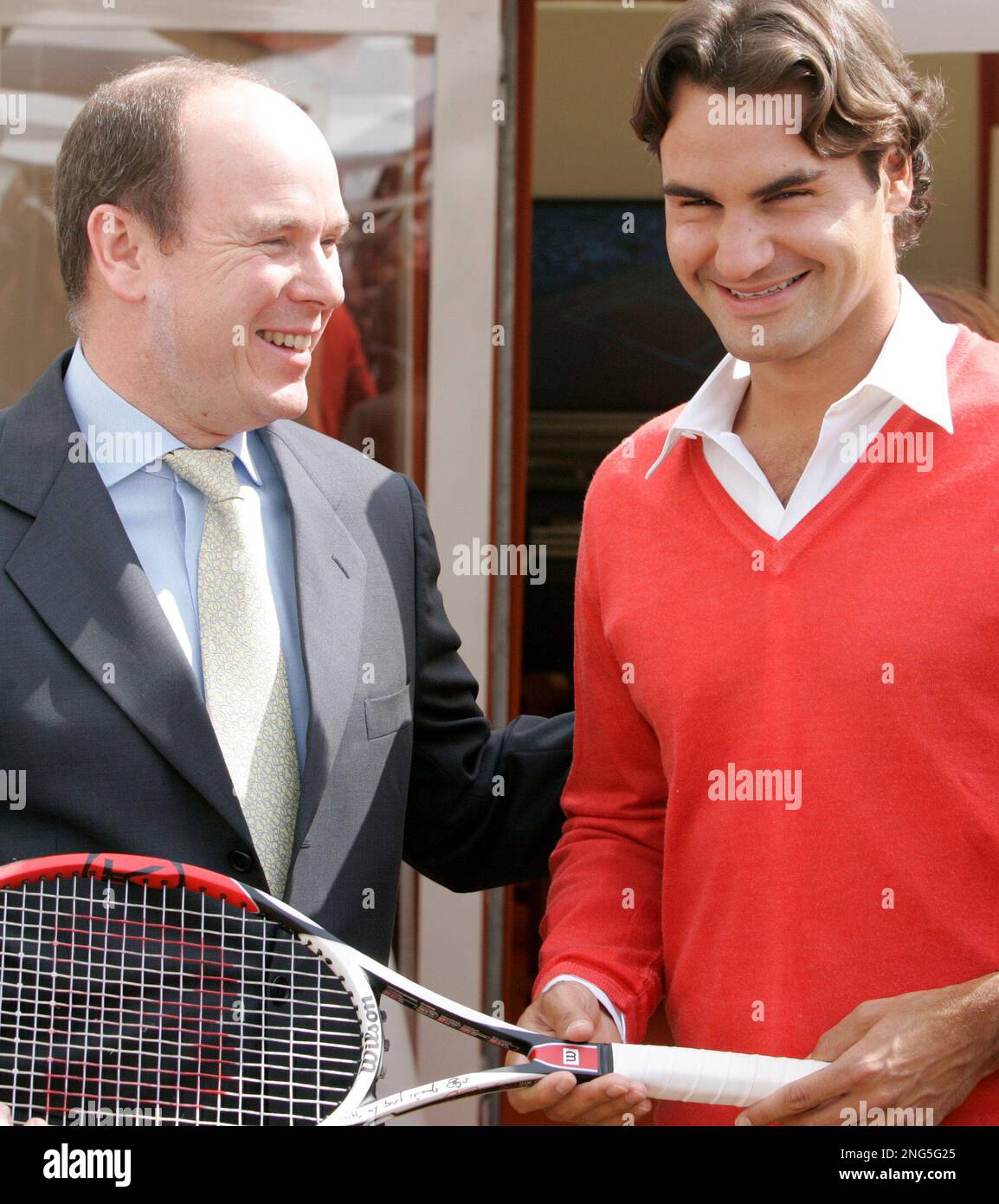 Swiss tennis player Roger Federer, right, gives one of his rackets to ...