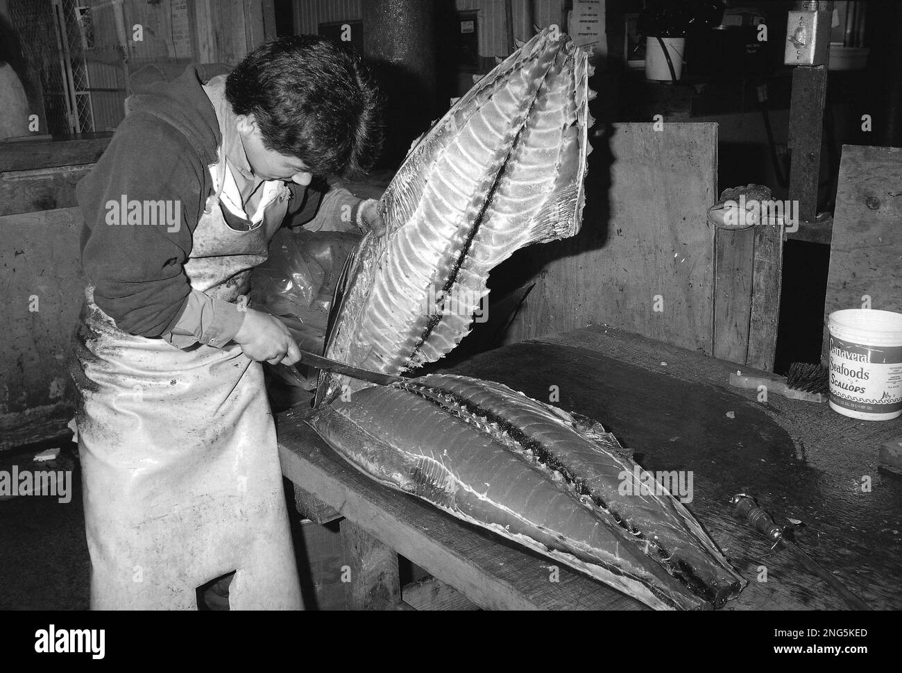 Wol-Ho Sin cuts apart a large blue fish tuna at his fish stall at New ...