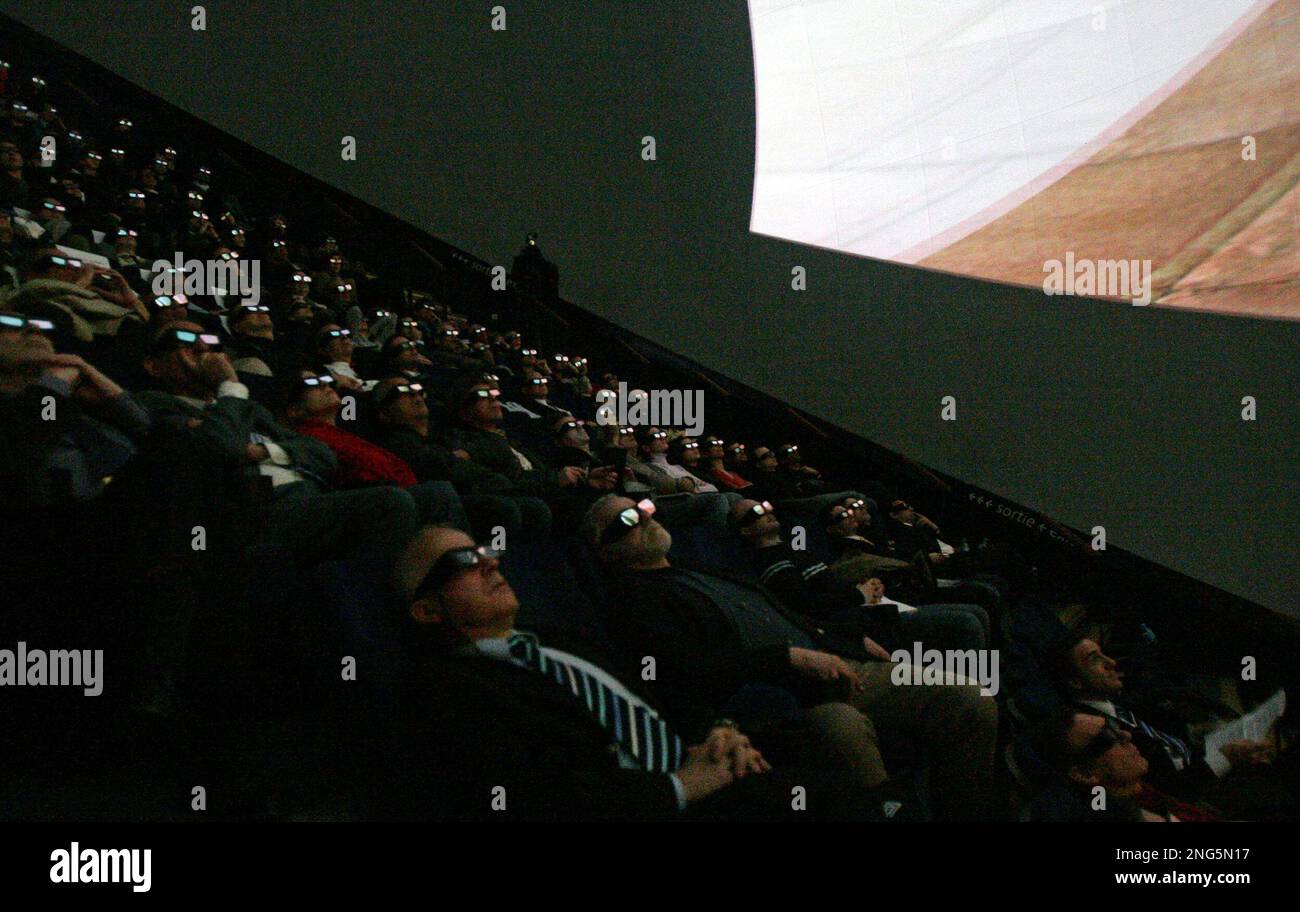 Spectators wearing 3D glasses watch a 3D presentation of French ...