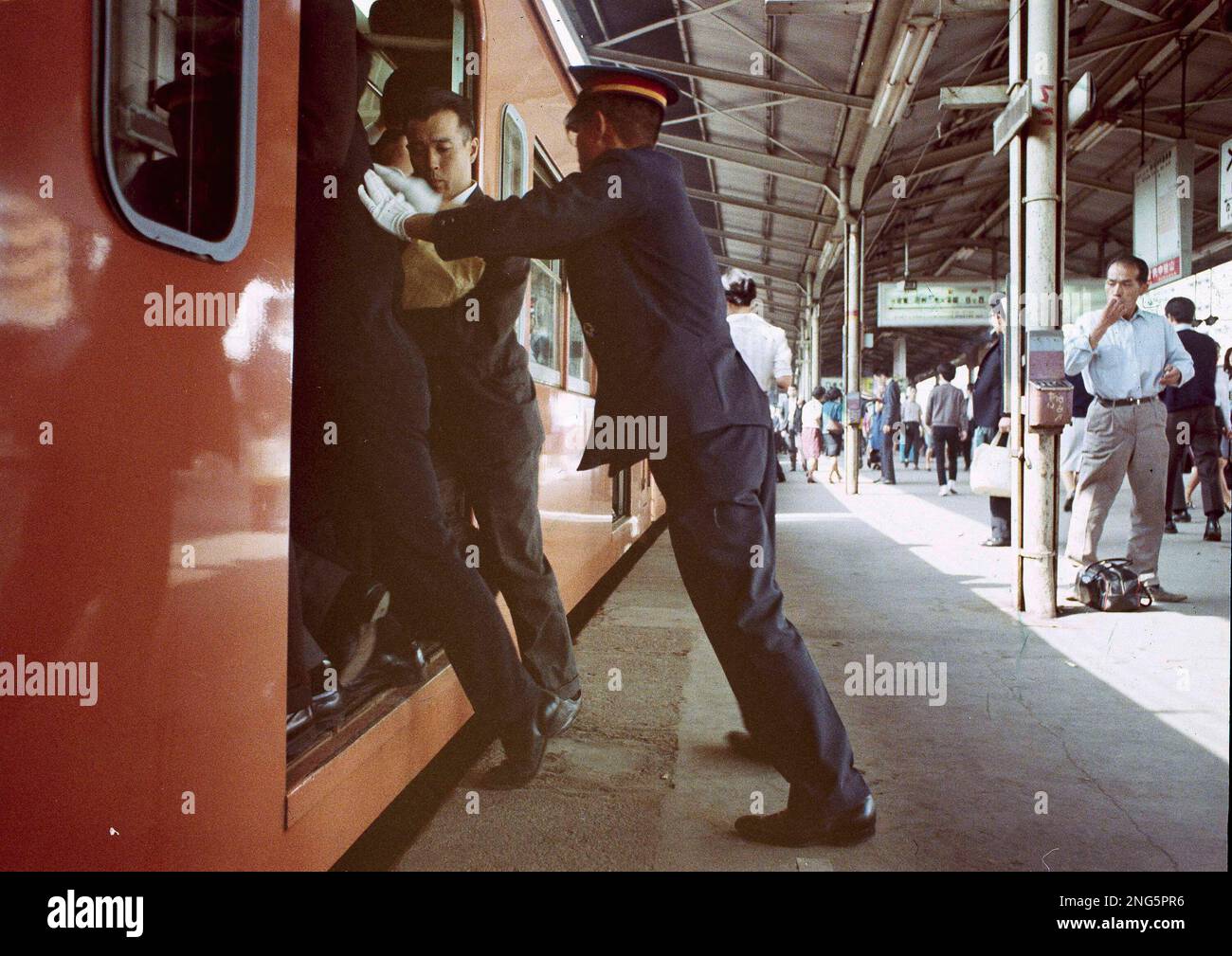 A professional subway pusher shoves commuters onto a train in Tokyo ...