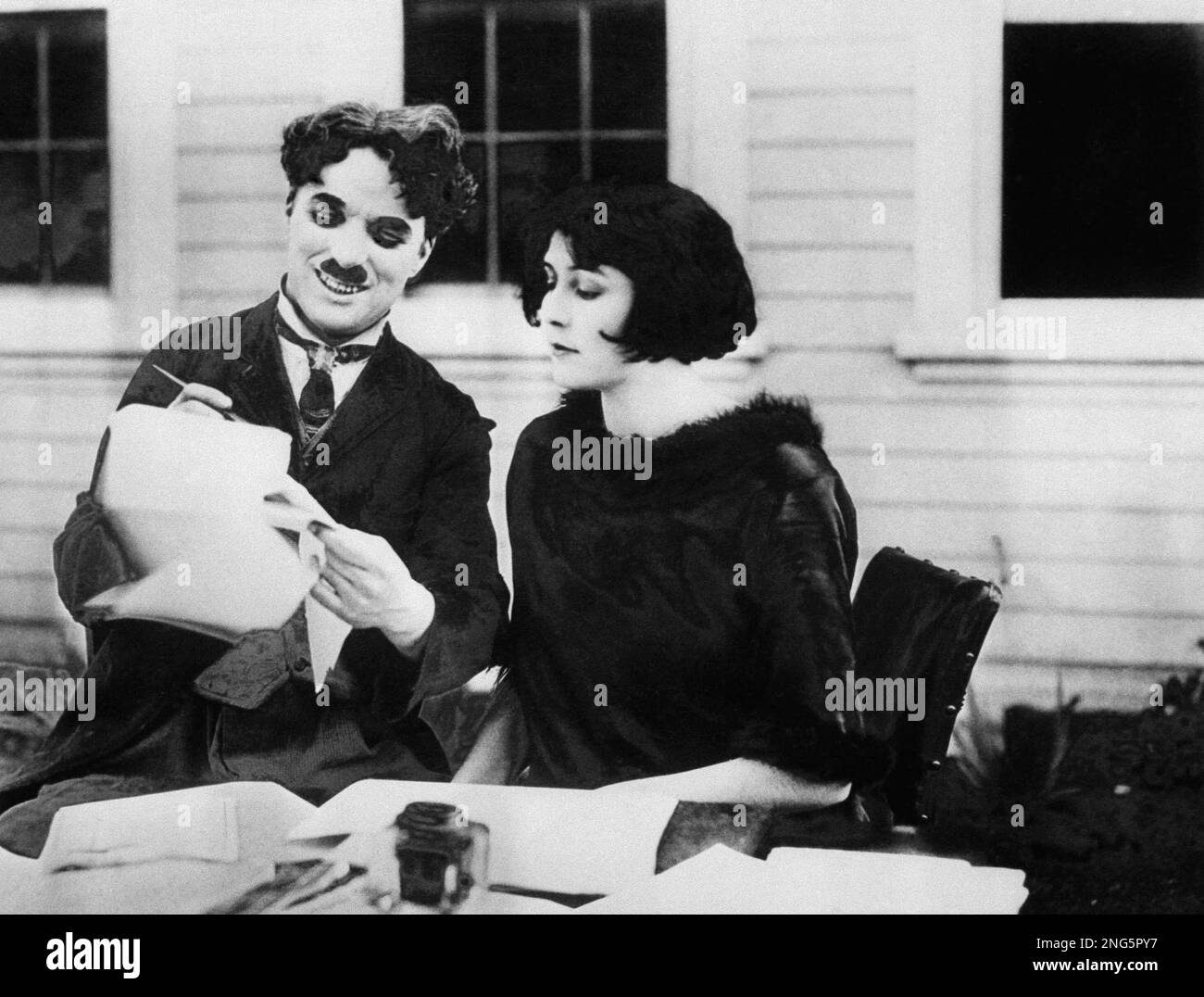 Charlie Chapin, in costume, sits with his leading lady Lita Grey on ...