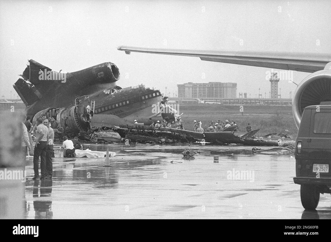 Medical personnel, left, cover bodies of victims of the Delta L-1011 ...