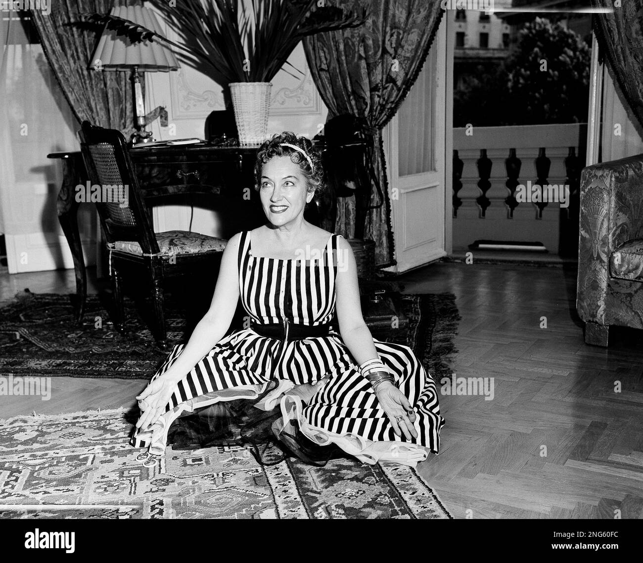 Actress Gloria Swanson is seen in a seated pose practicing yoga in her ...