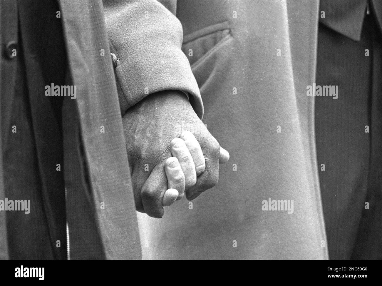 Two men, one black and one white, join hands as they sing during a ...