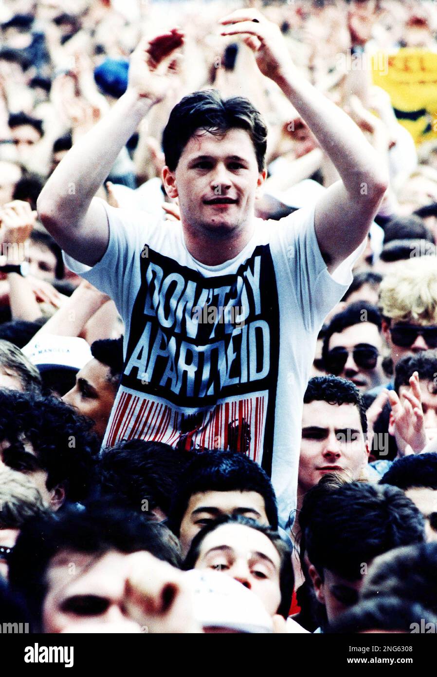 A member of the crowd applauds artists on the stage at Wembley Stadium ...