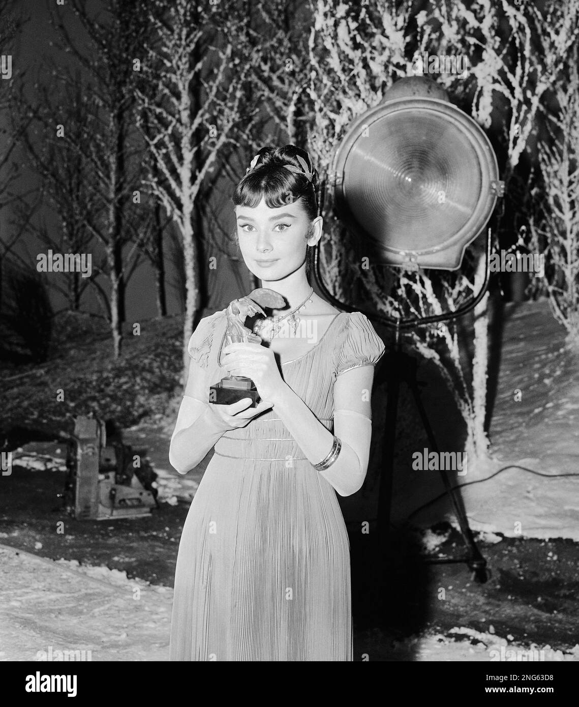 Screen star Audrey Hepburn holds the "Victory of Samothrace" statue ...