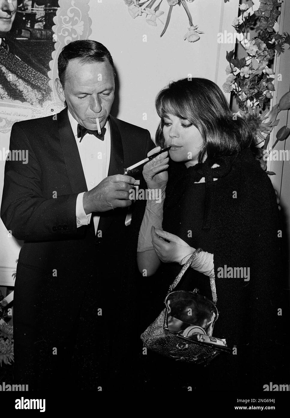 Singer Frank Sinatra lights a cigarette for actress Natalie Wood as ...