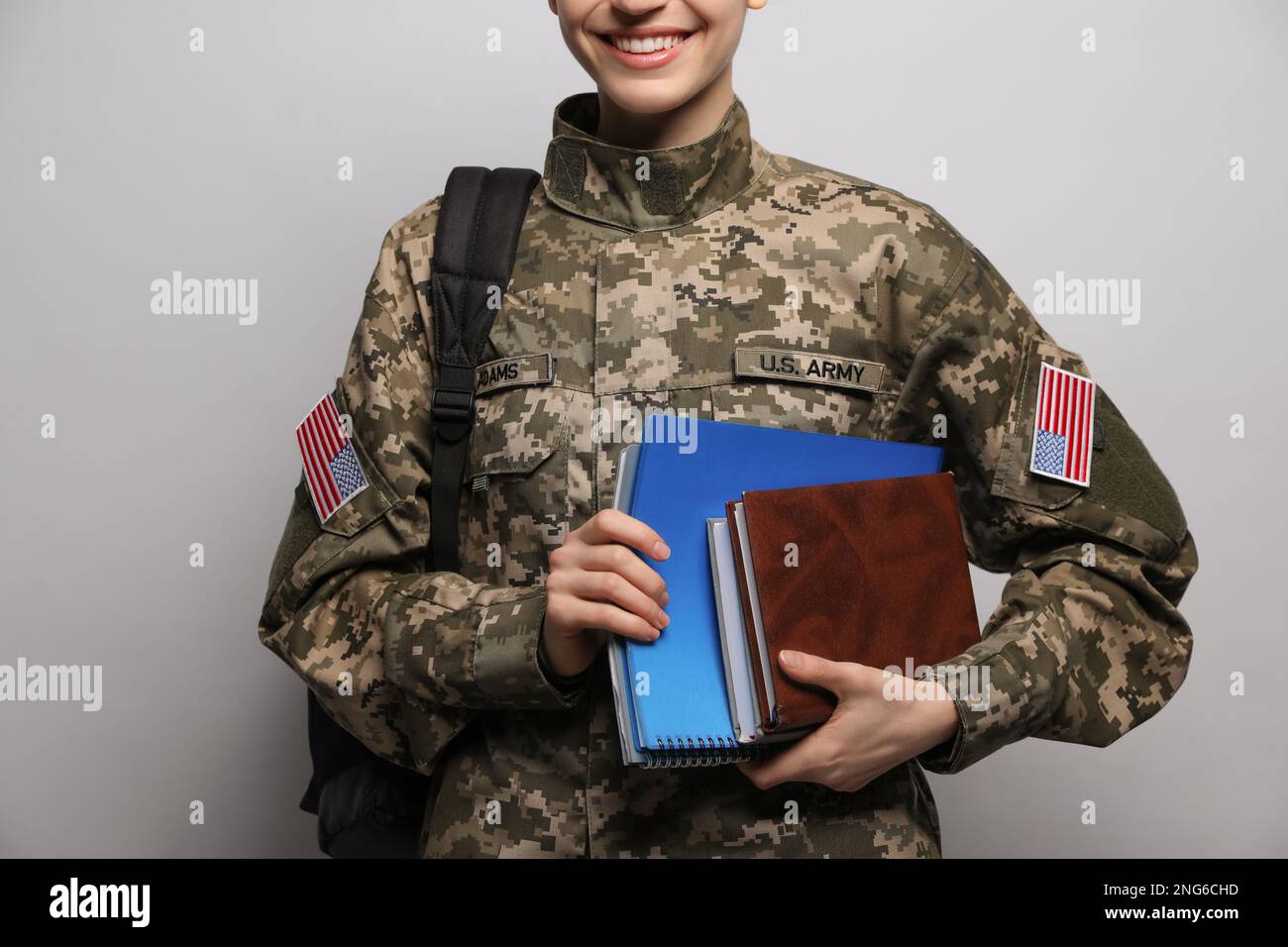 Female cadet with backpack and notebooks on light grey background ...