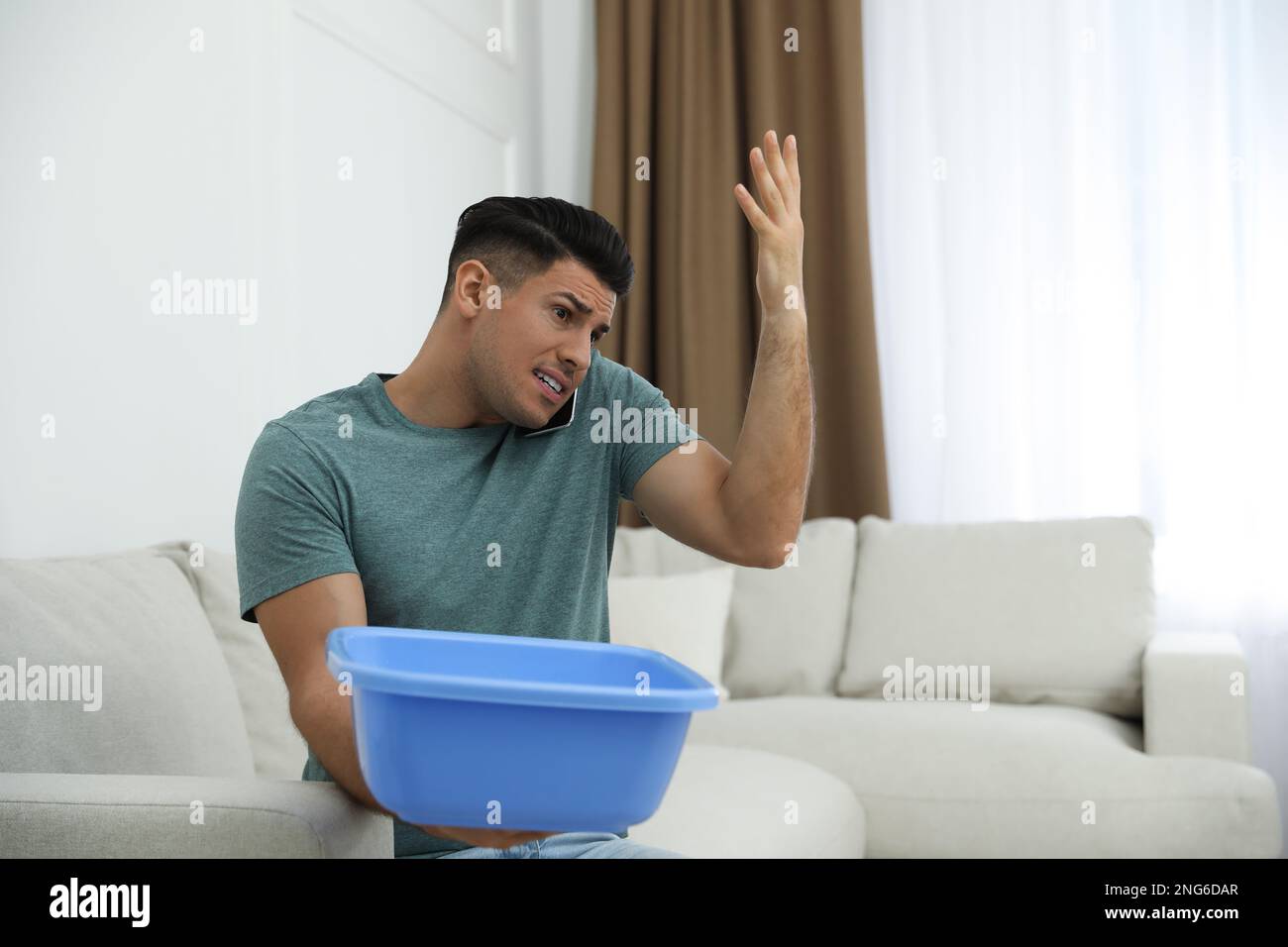 Emotional man calling roof repair service while collecting leaking ...