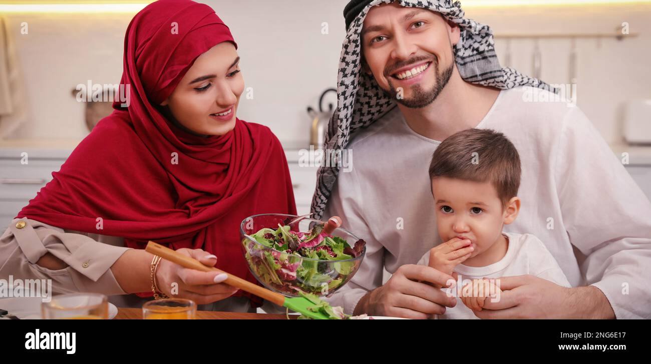 Happy Muslim family eating together at table in kitchen. Banner design ...