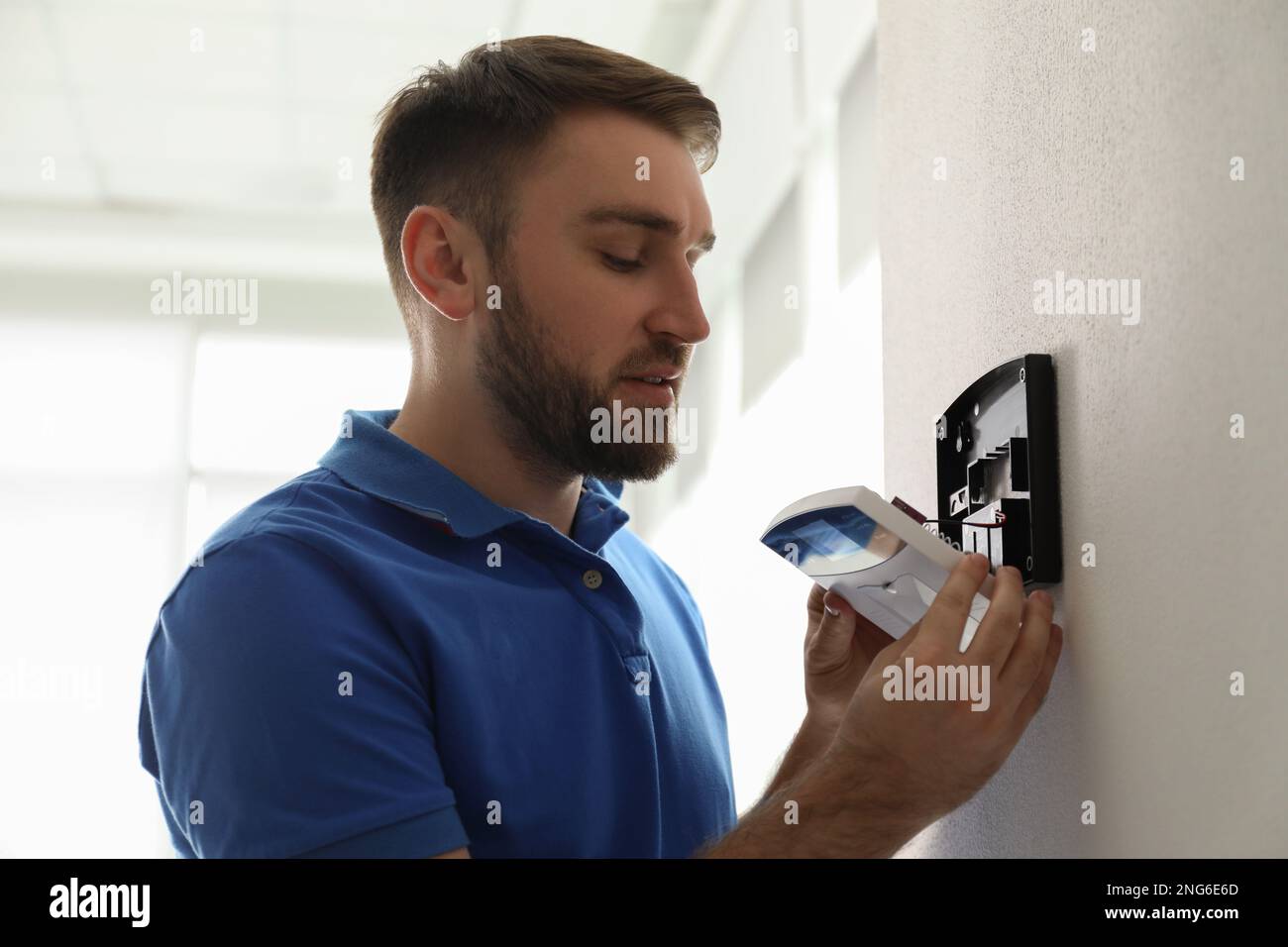 Man installing home security system on white wall in room Stock Photo ...