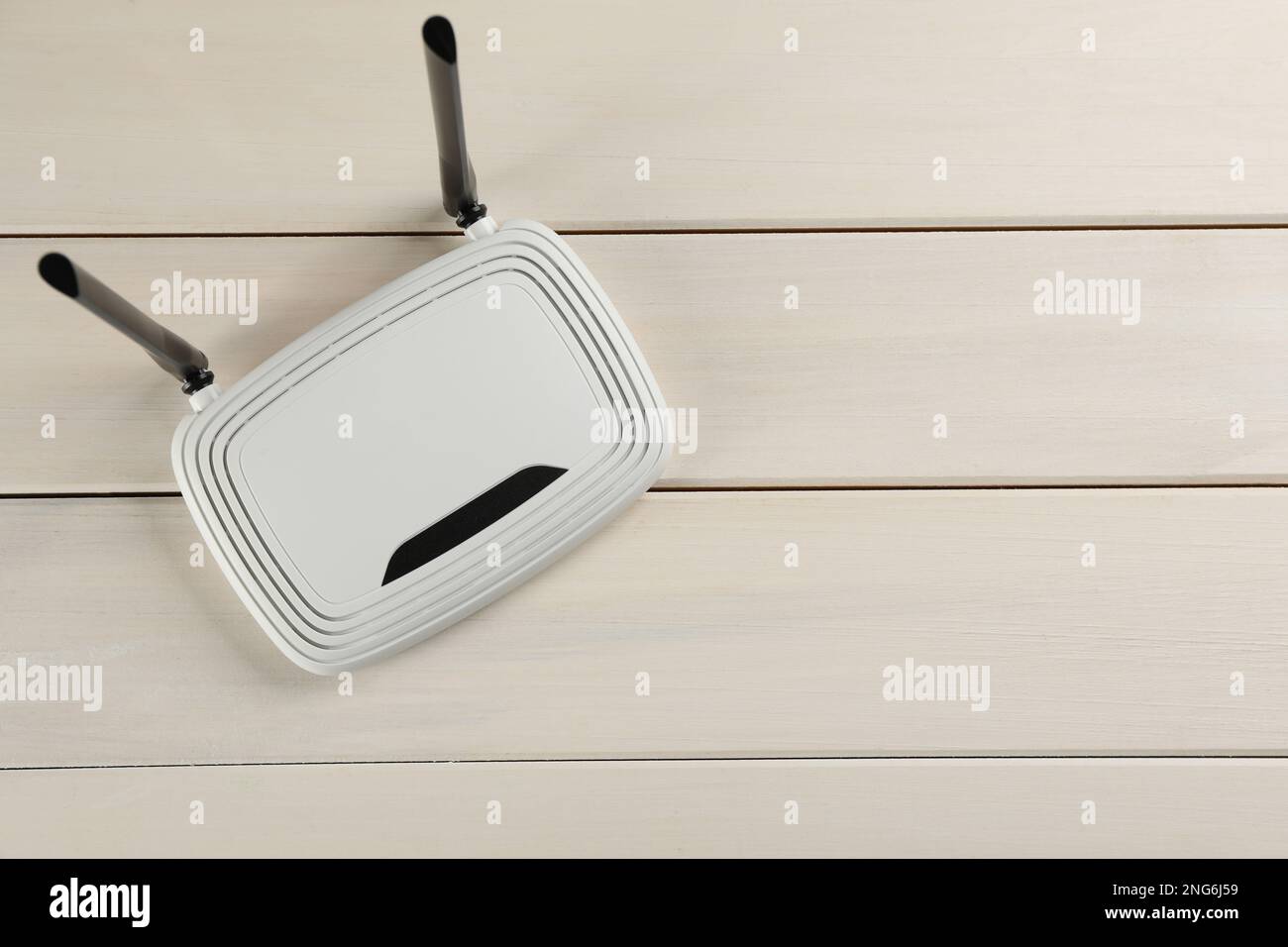 Modern Wi-Fi router on white wooden background, top view. Space for ...