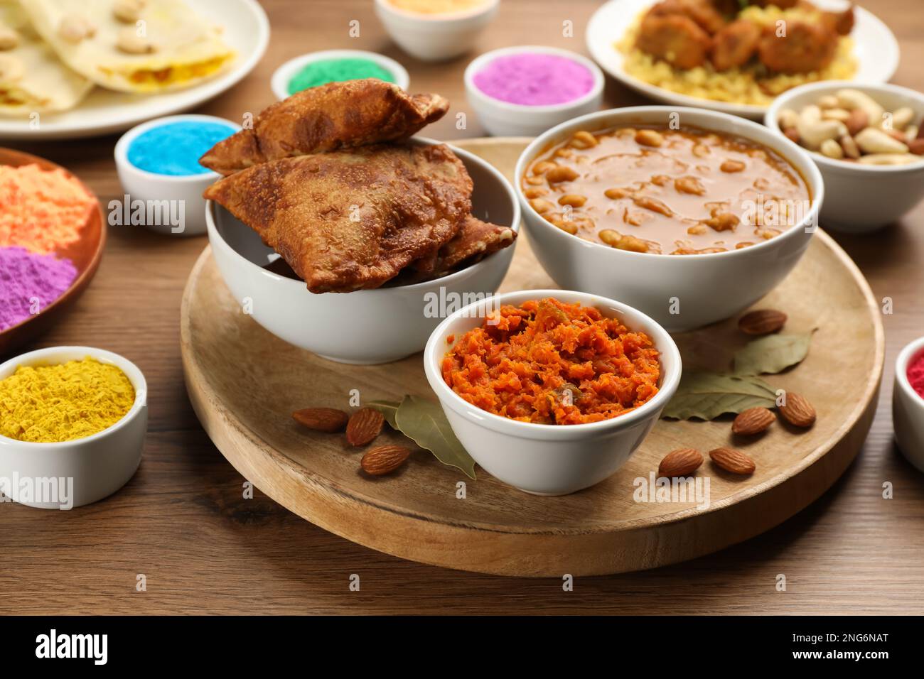 Traditional Indian food and color powders on wooden table, closeup ...