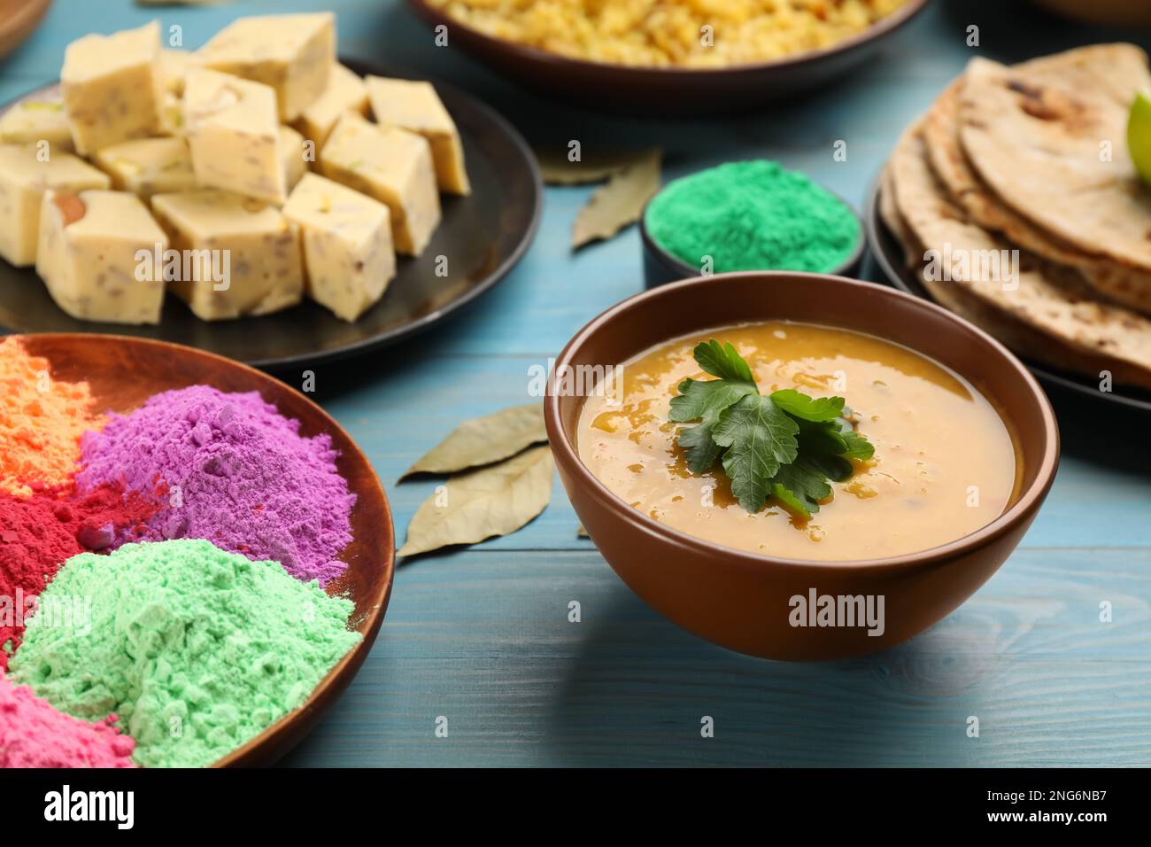 Traditional Indian food and color powders on light blue wooden table ...