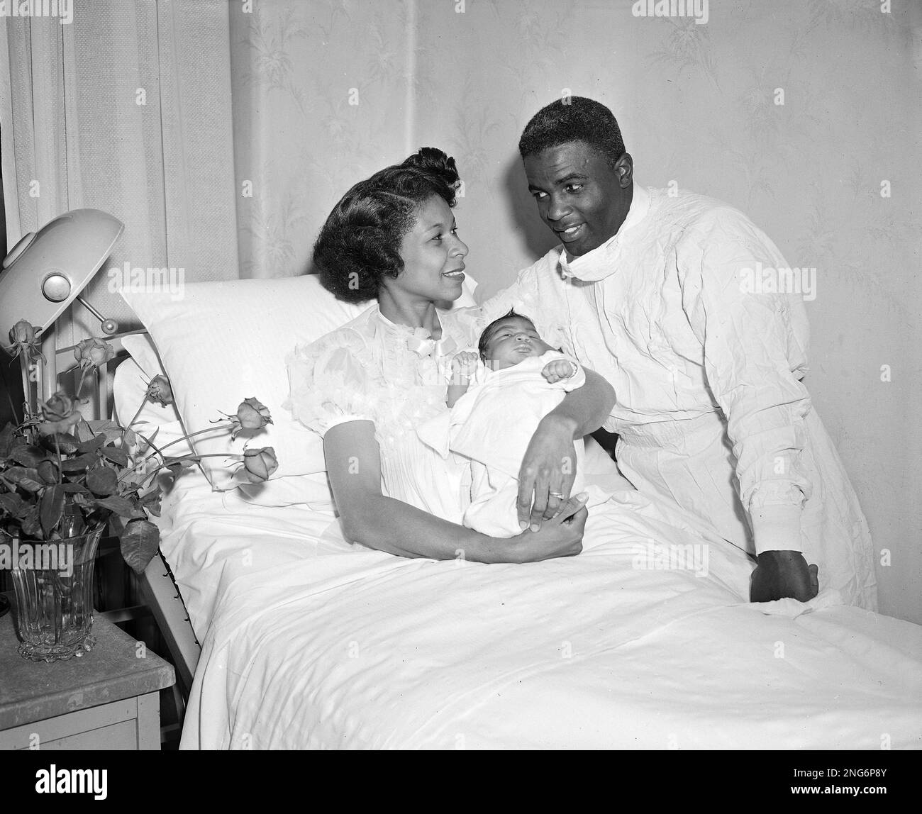 Baseball legend Jackie Robinson looks at this wife Rachel as she holds ...