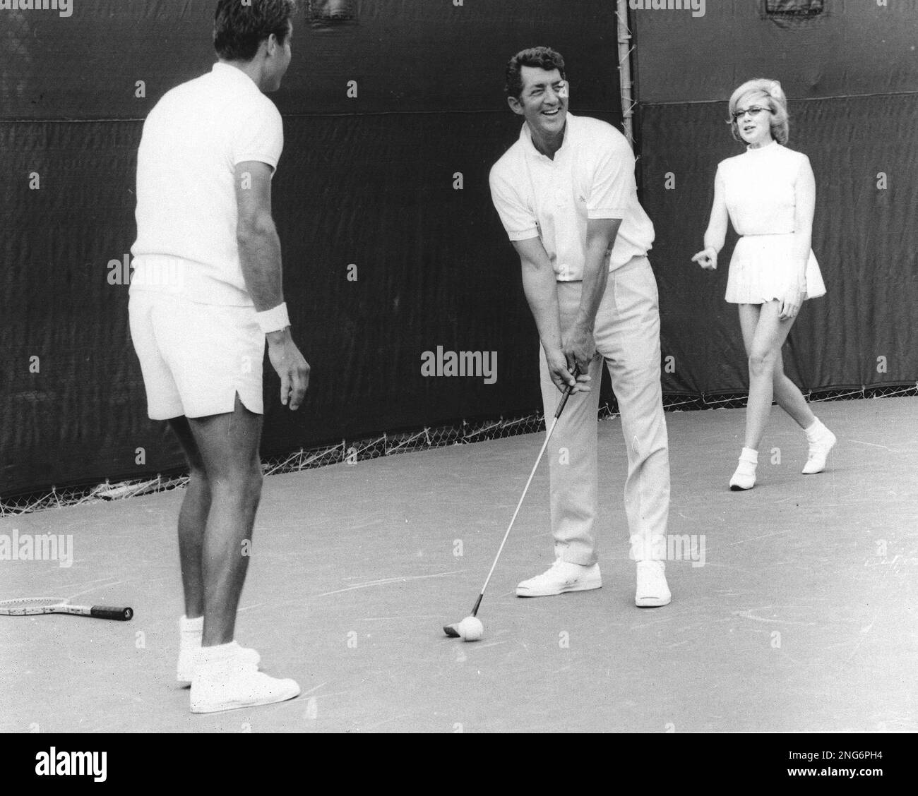 Entertainer Dean Martin starts to play golf on a tennis court while ...