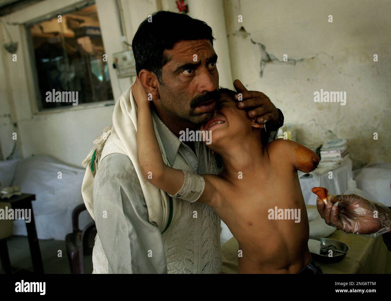 Sabir Hussein Shah holds his nine-year-old son Zeeshan while he is ...