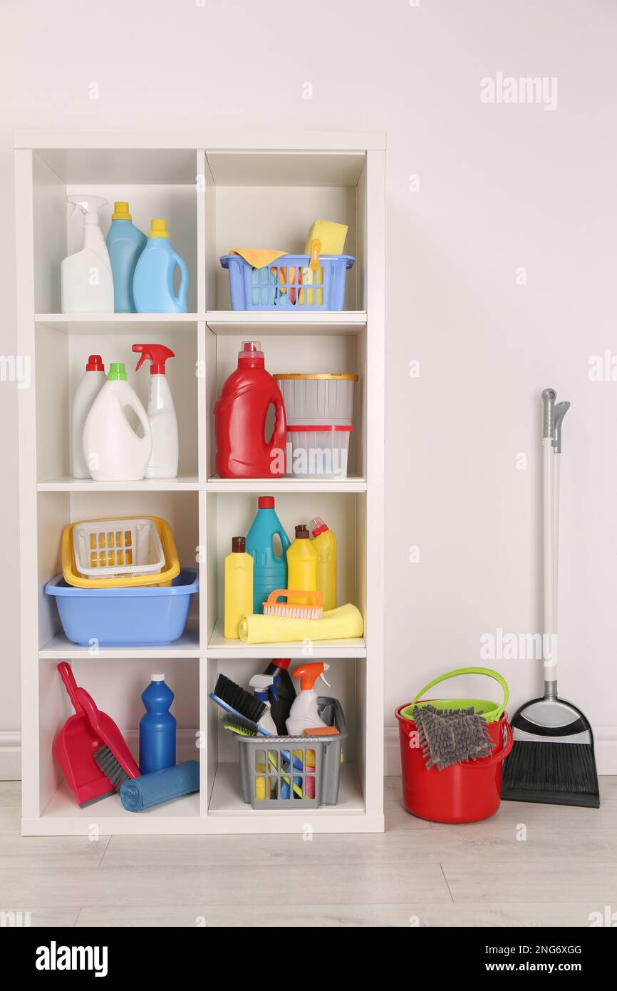 Shelving unit with detergents and cleaning tools near white wall ...