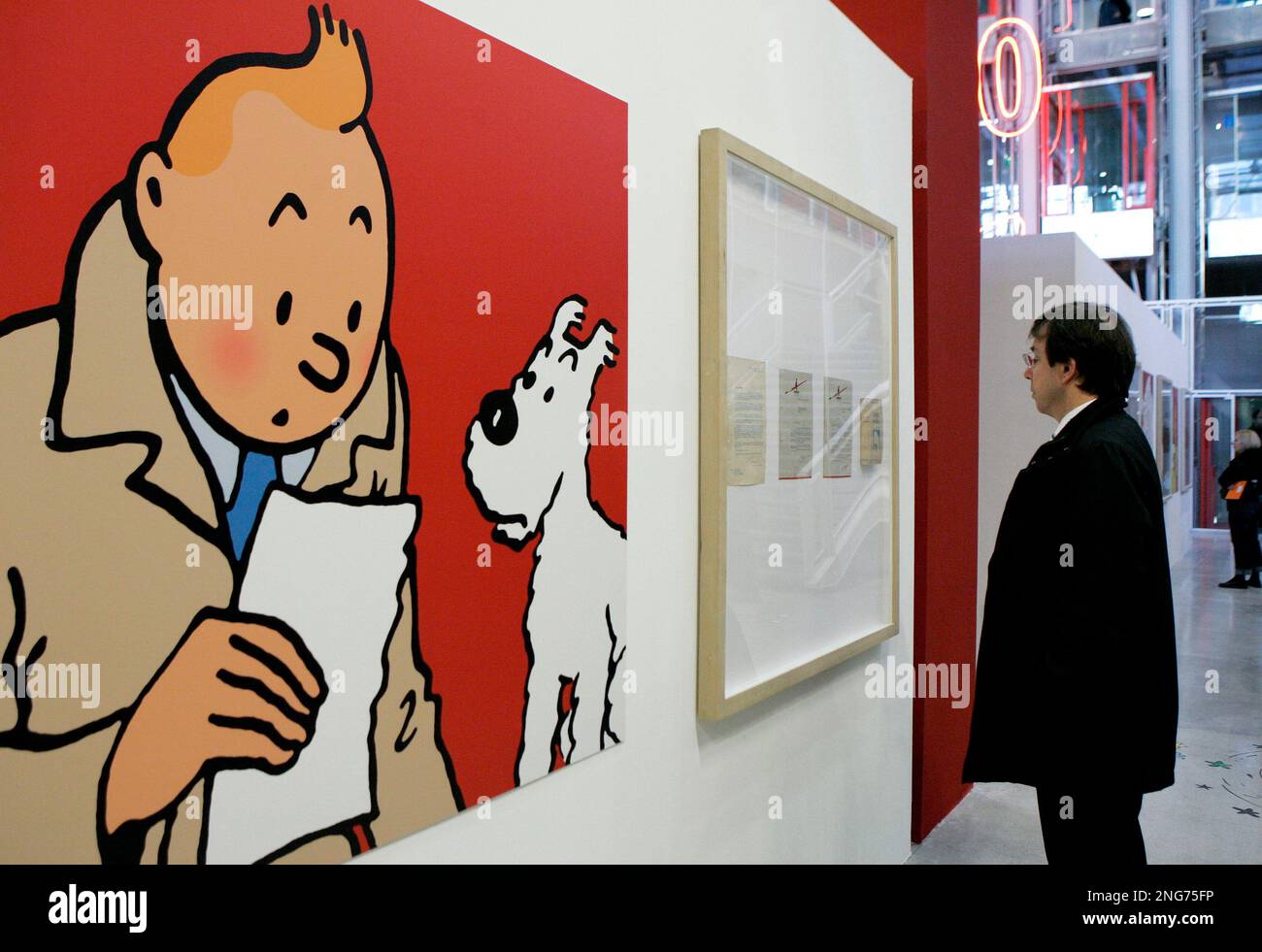 A visitor looks at original letters and an enlarged cartoon of Tintin ...