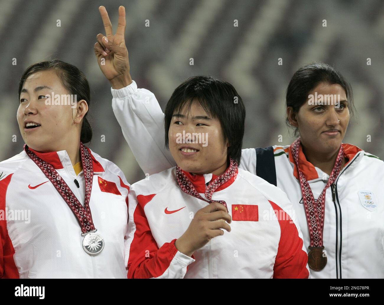 India's Krishna Punia, bronze, right, gesutres from behind China's Song Aimin, gold, and China's ...