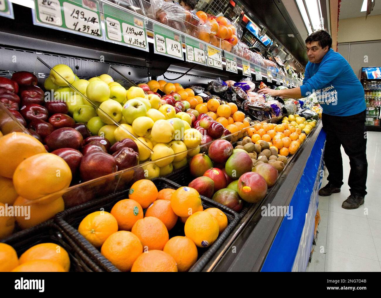 Grocery store owner Gilles Robin works on his fruits vegetable display ...