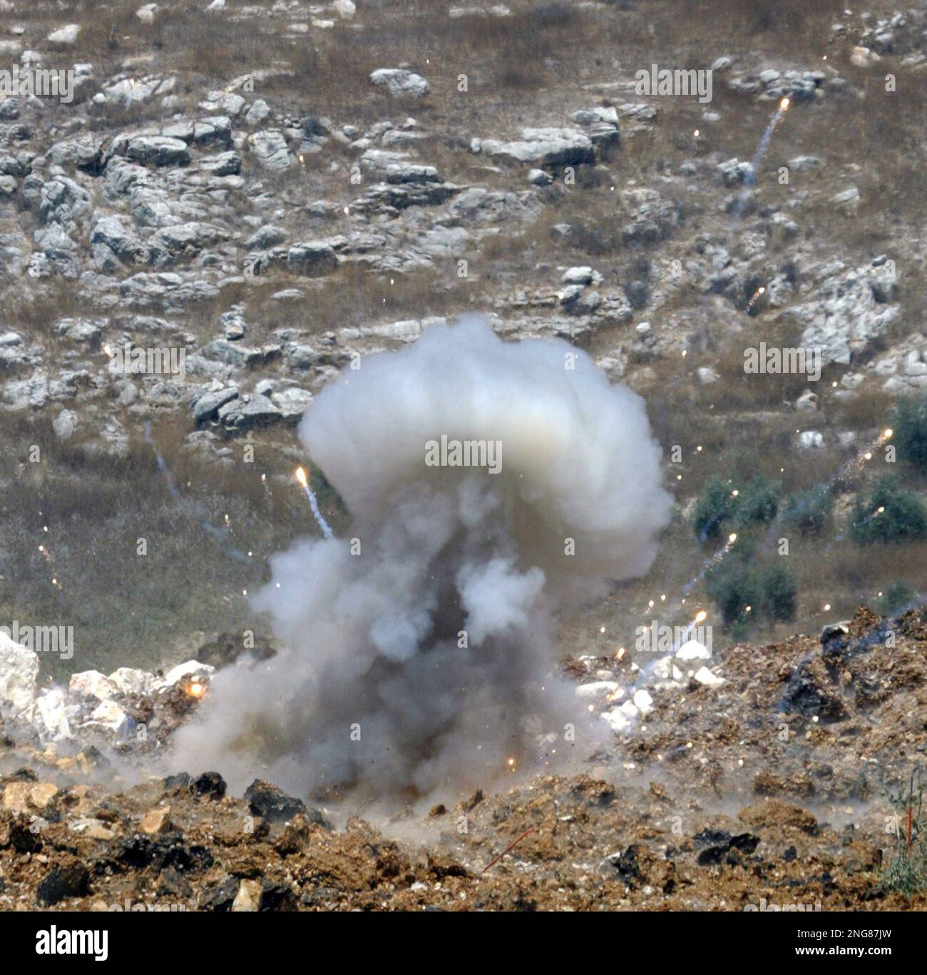Stones and dirt are blasted into the air as unexploded ordnance from a ...