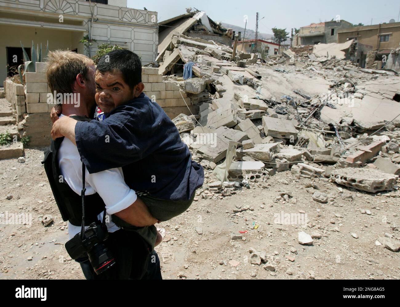 A press photographer carries a man, as they walk through the rubble ...
