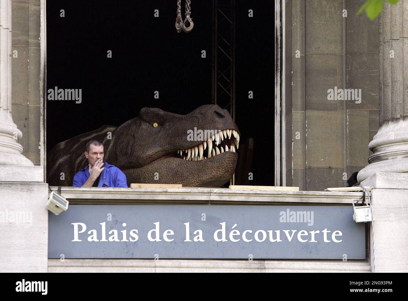 A worker smokes a cigarette before removing a T-Rex dinosaur replica ...