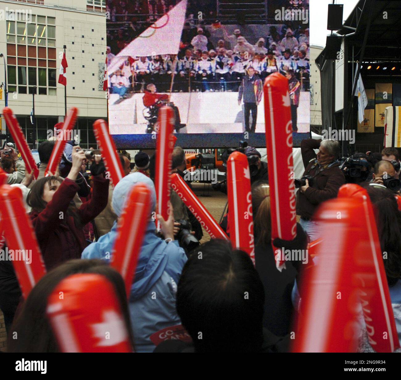 People watch the Turin Olympics Closing Ceremonies on a giant screen ...