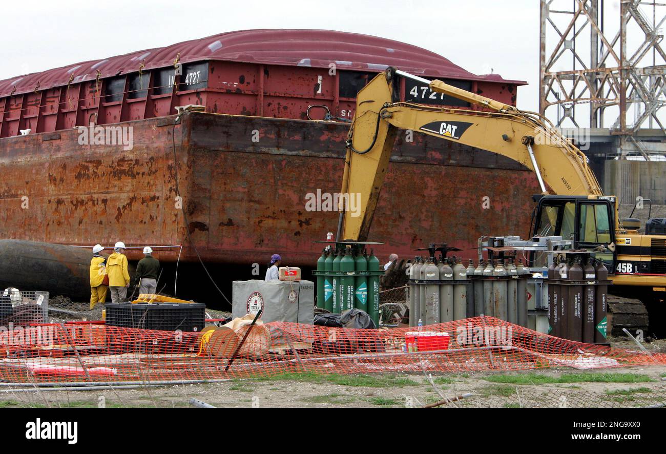 Workers use inflatable bags to raise the barge that came through the ...