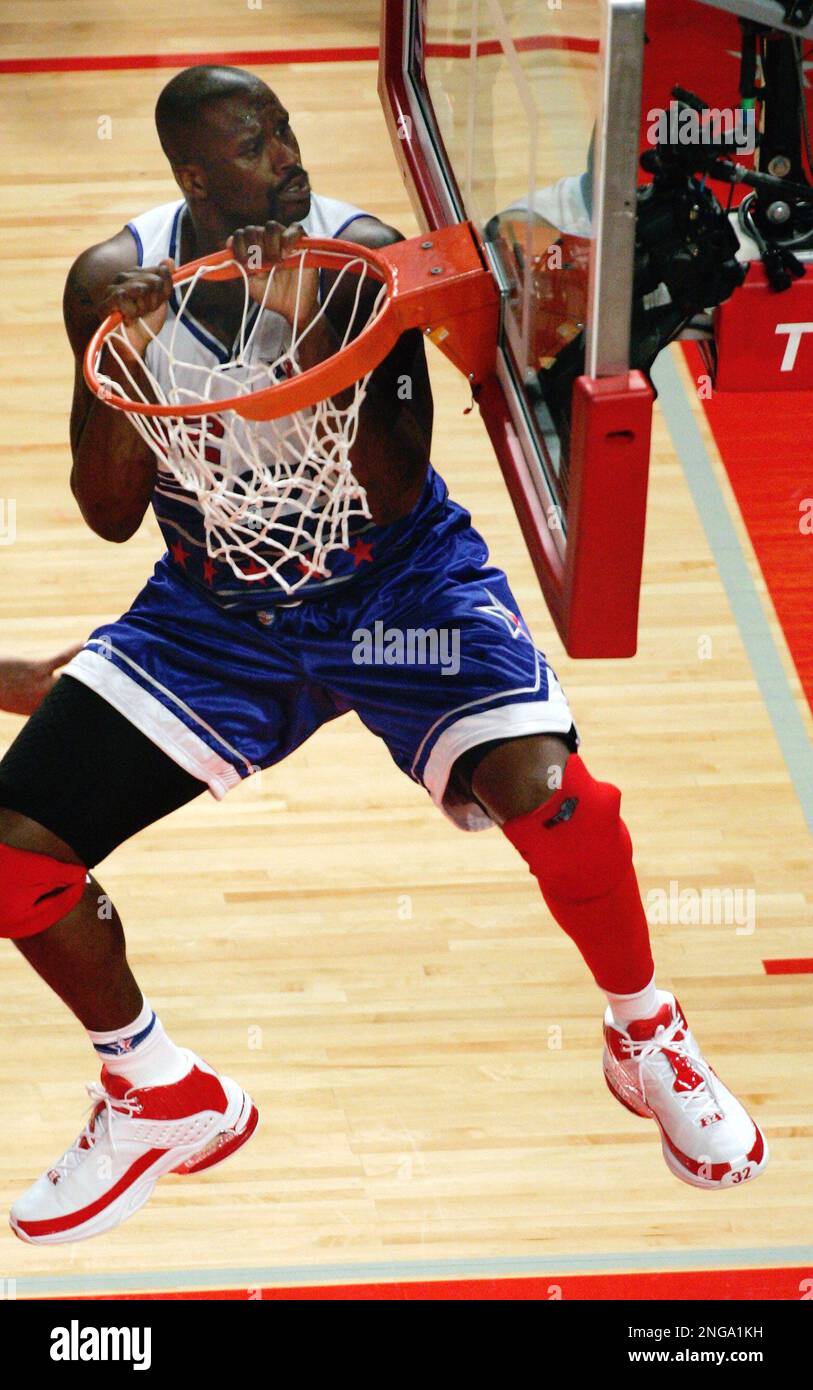 Shaquille O'Neal hangs on the rim and stares at the remote mounted ...