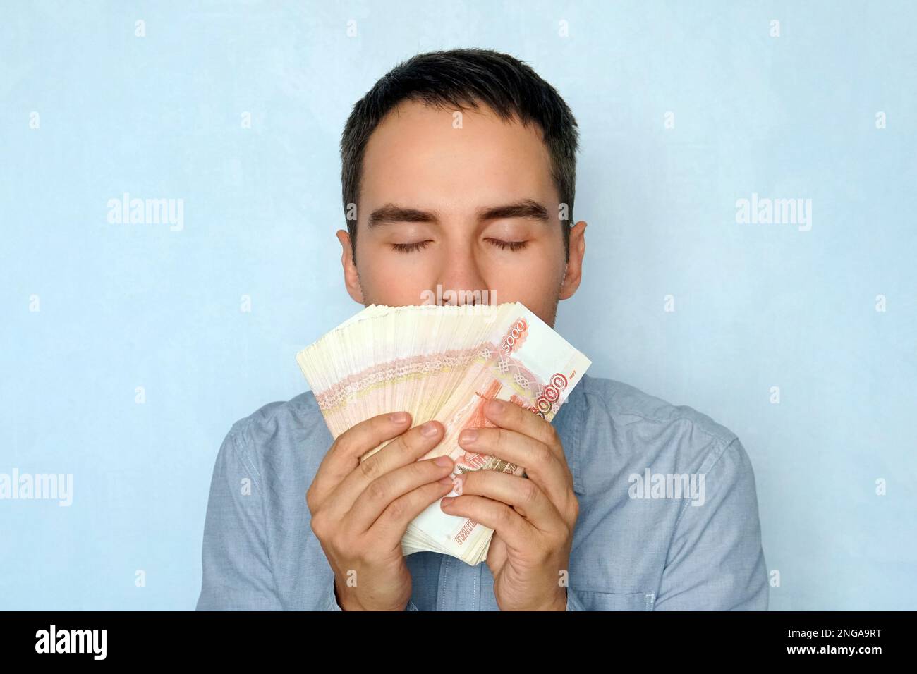 Man sniffing dollars. The sweet smell of money. Young guy sniffing 5000 ...