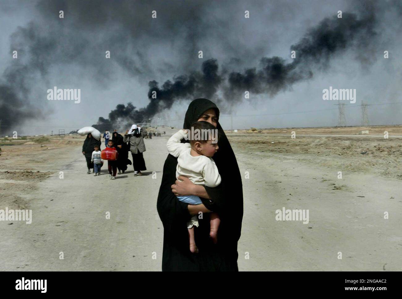 An Iraqi woman carries her young child on the outskirts of Basra as she ...