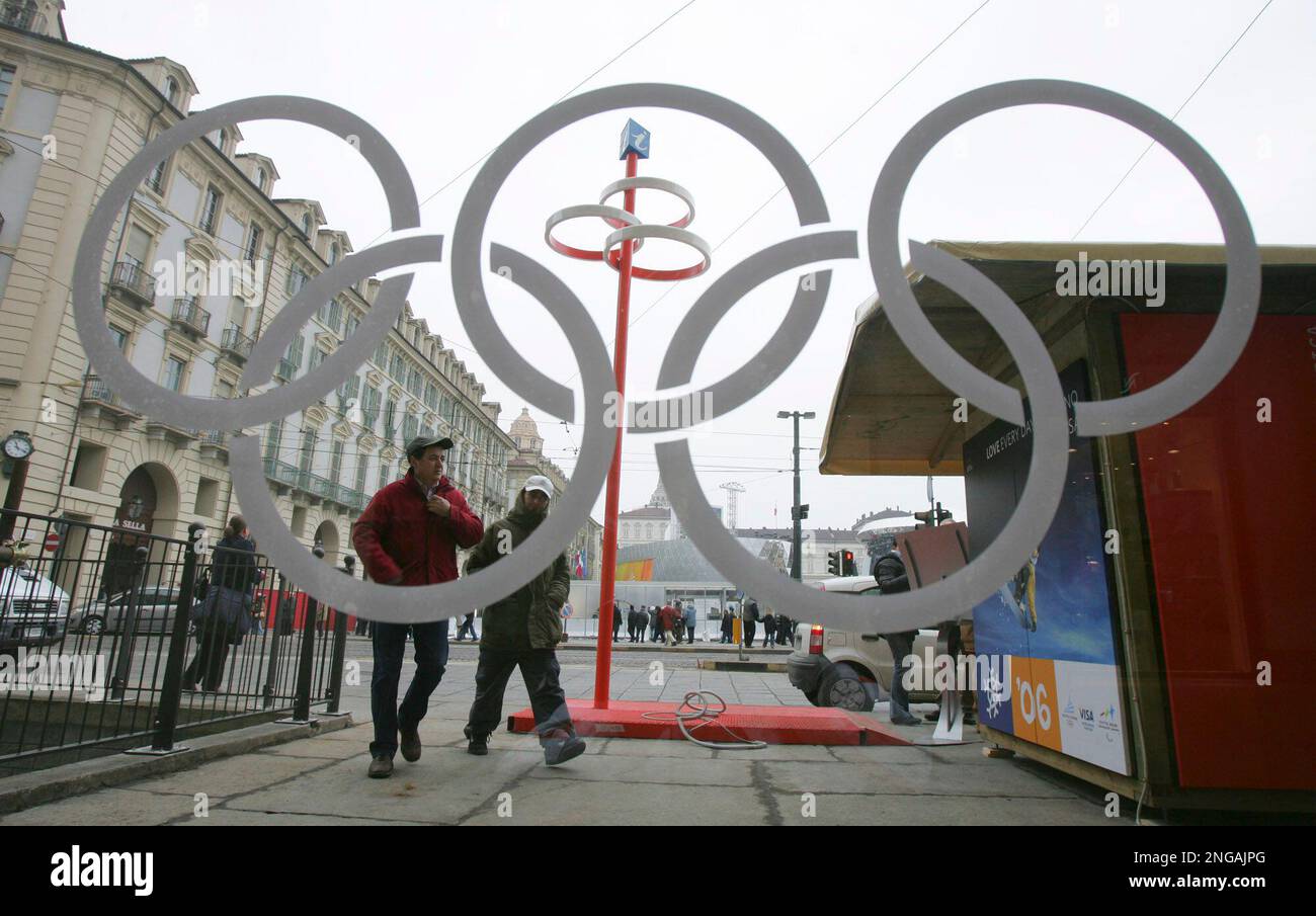People walk past an Olympic logo in downtown Turin, Italy, Sunday Feb ...