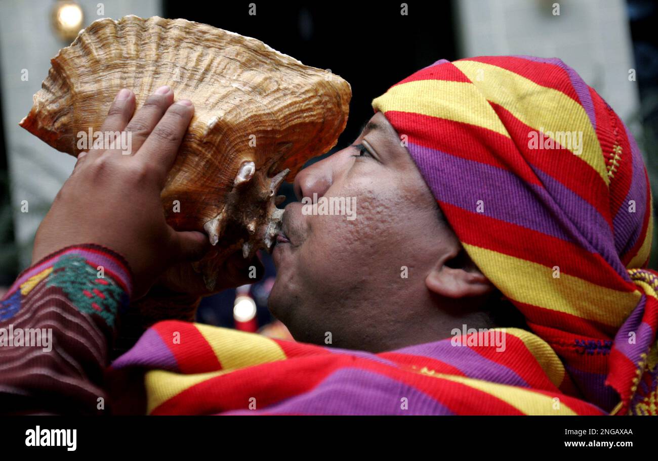 A Mayan performer blows a shell during an offical ceremony to ...