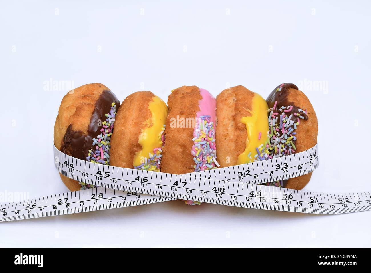 A measuring tape wrapped around five colourful doughnuts to illustrate ...
