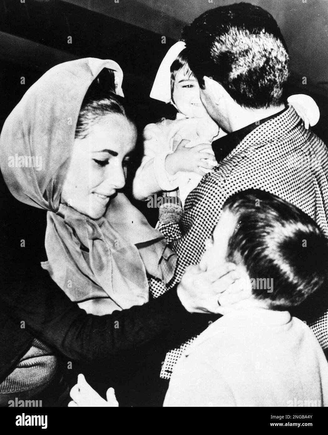 British actress Elizabeth Taylor fondles the face of one of her sons, 5 ...