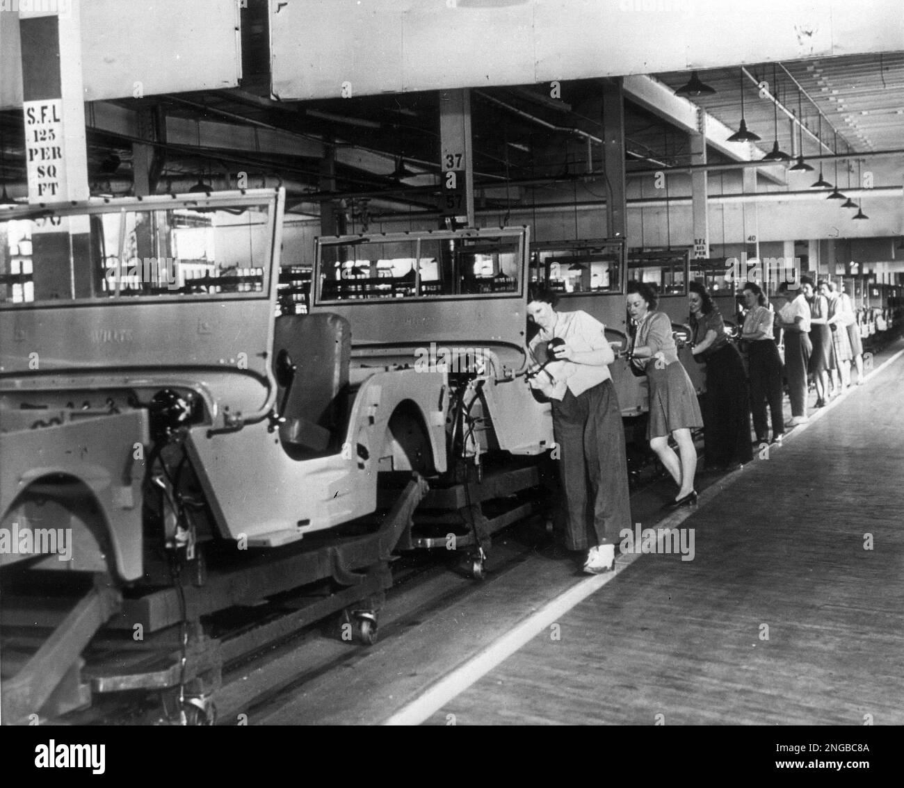 Assembly line workers add parts to jeeps for use by civilians at the ...