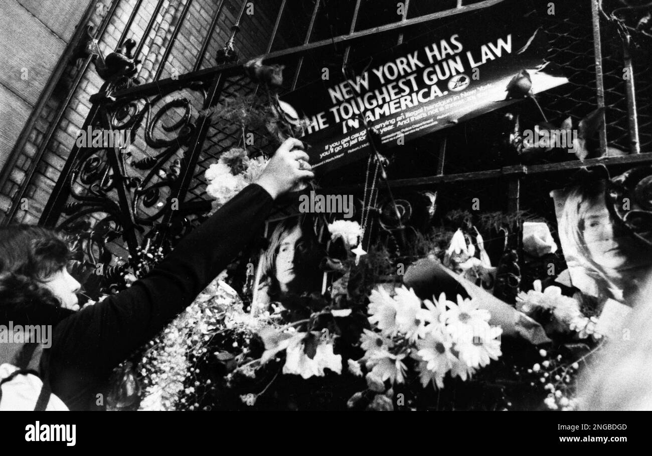 A woman adds a flower to the gate at the Dakota apartment building in ...
